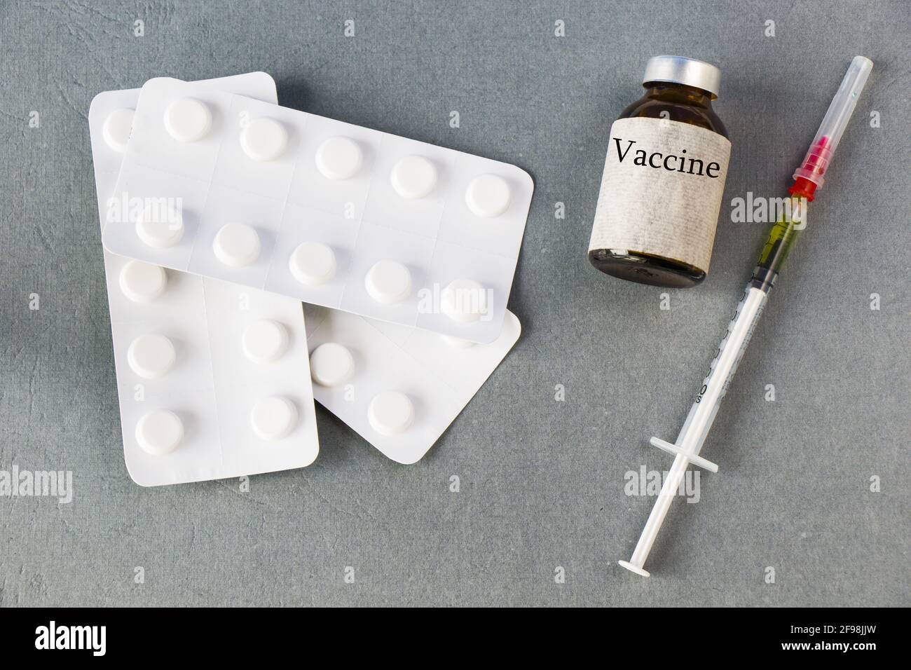 Top view of a vaccine ampule and a syringe with tablets on white ...