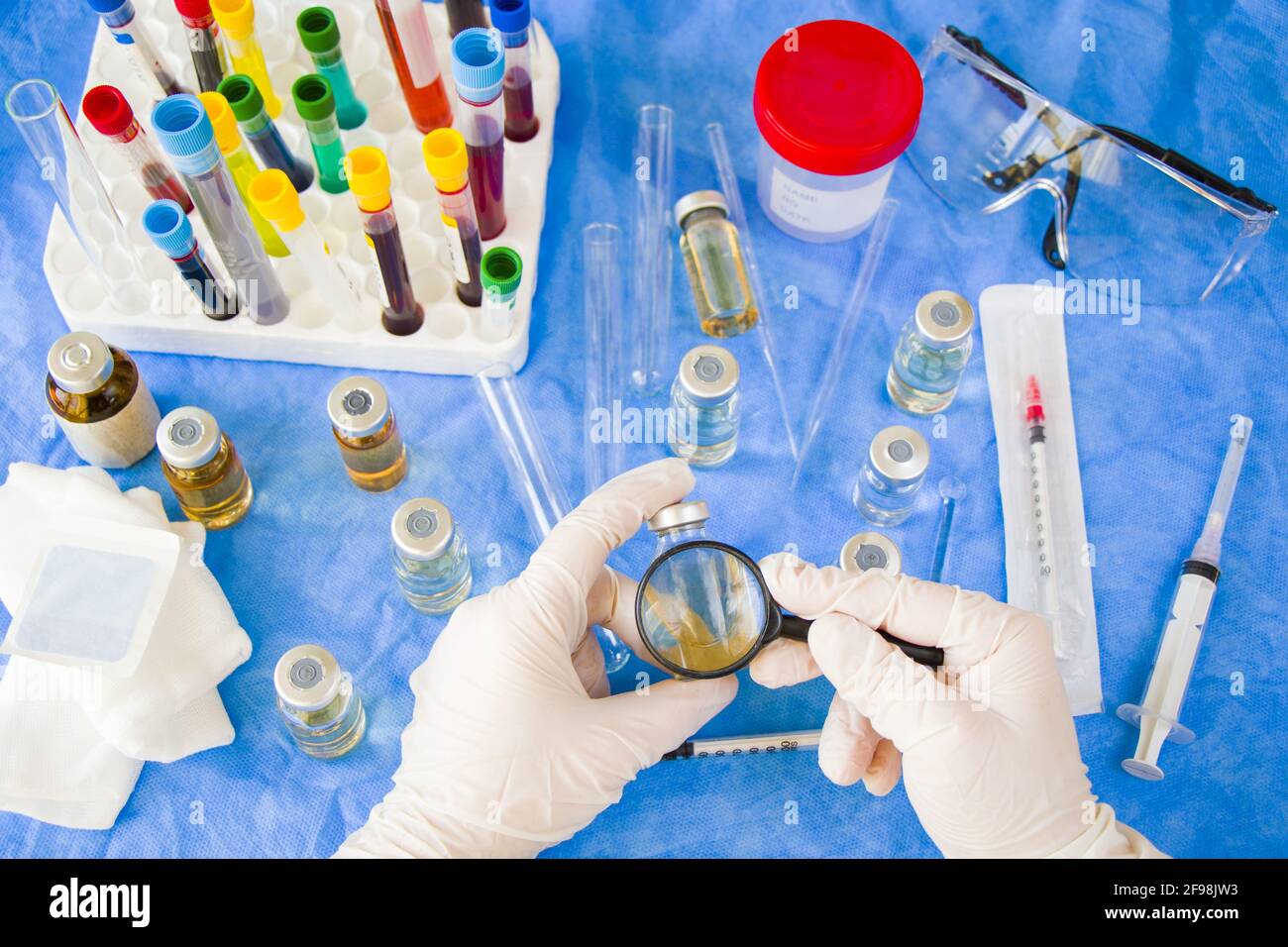 Closeup shot of a doctor looking at a bottle through a magnifying glass ...