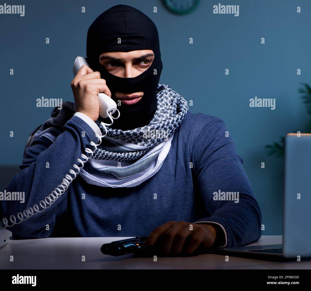 The terrorist burglar with gun working at computer Stock Photo - Alamy