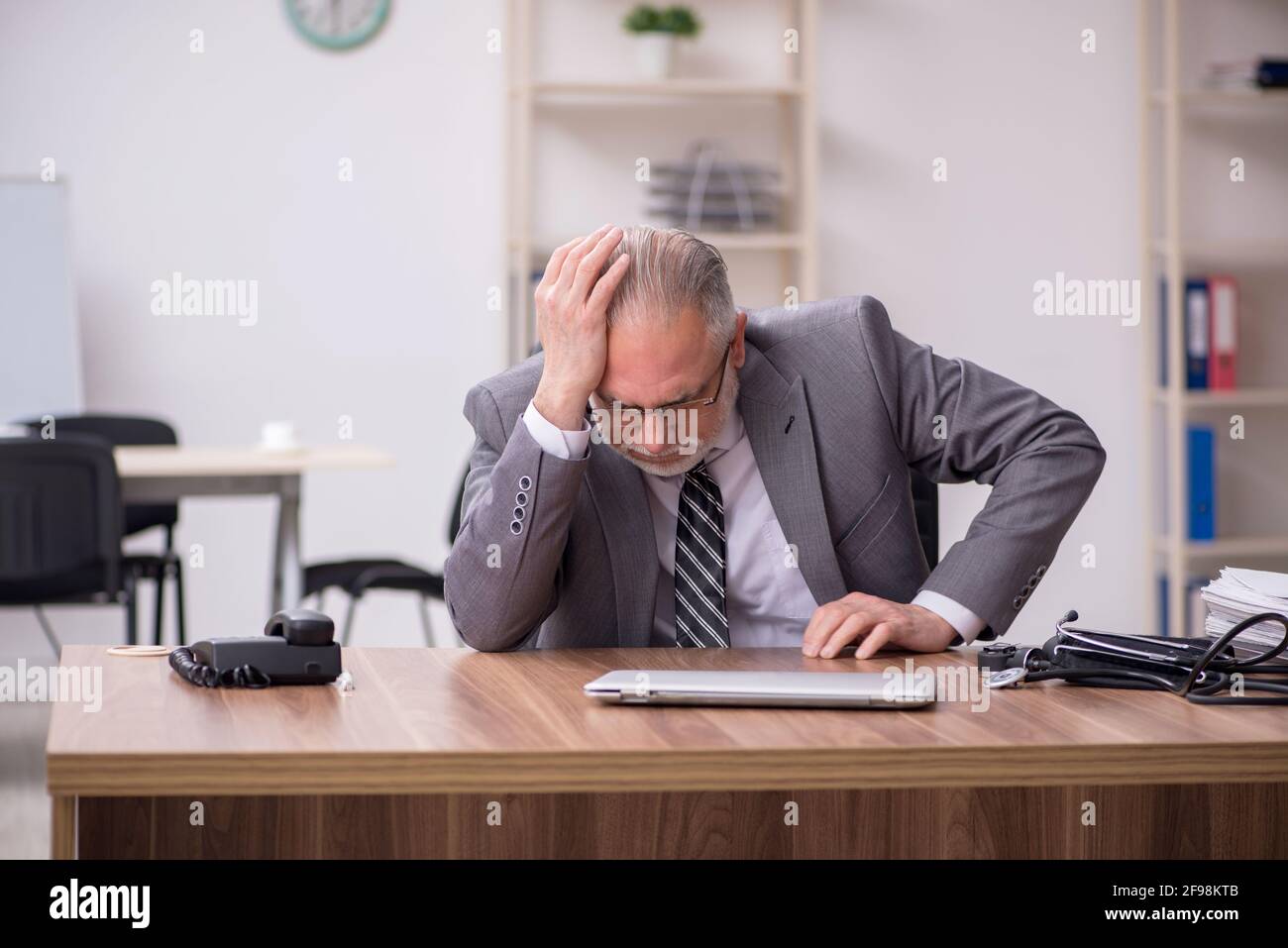 Aged male employee feeling bad in the office Stock Photo - Alamy