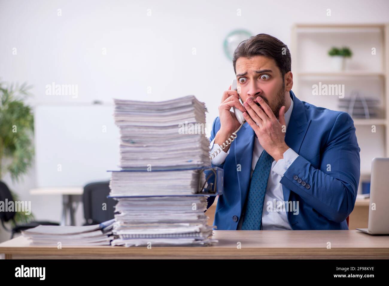 Young male employee and too much work in the office Stock Photo - Alamy