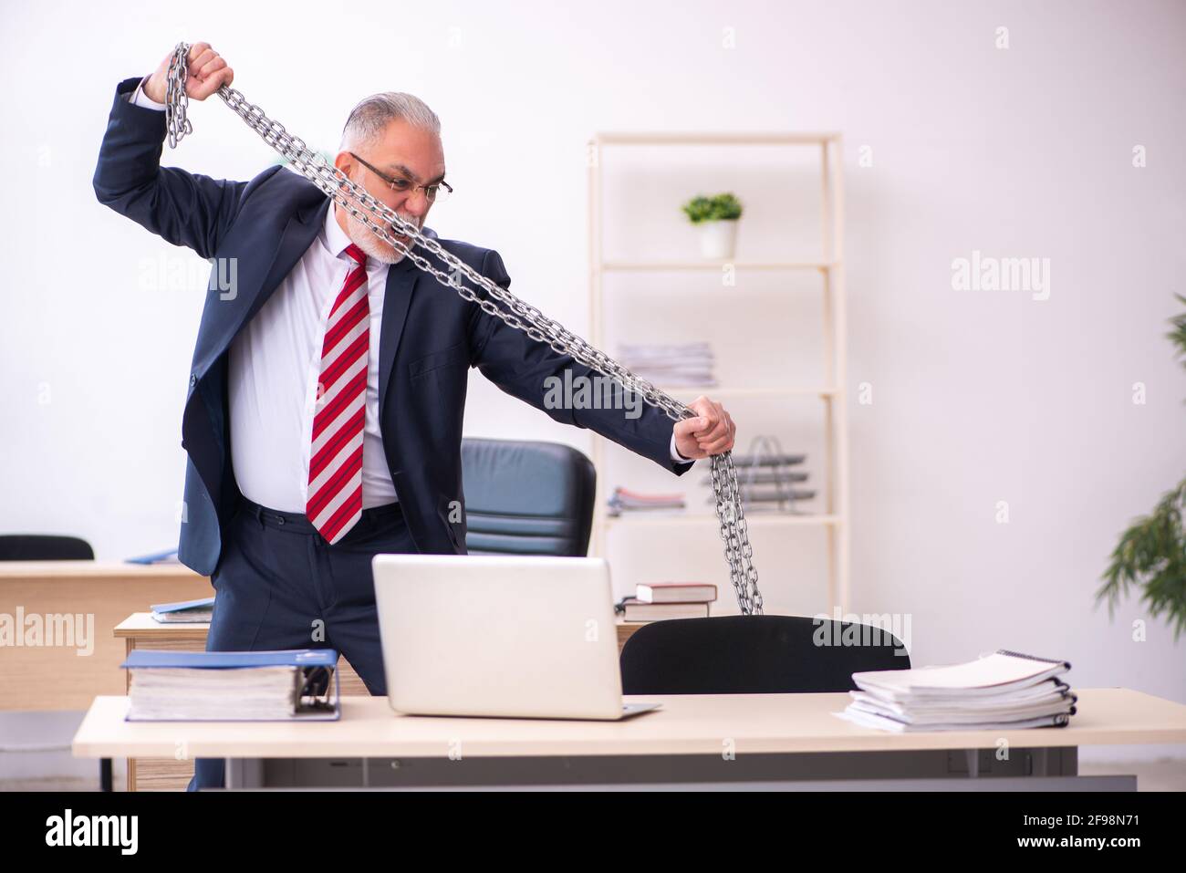 Old male employee holding chain at workplace Stock Photo - Alamy