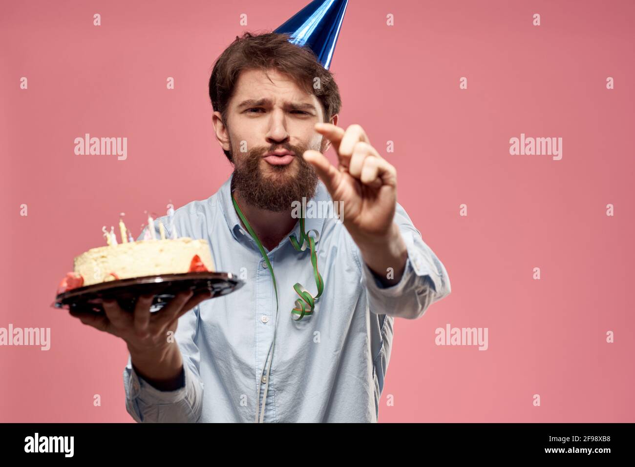 Man with cake in a plate and in a blue shirt on a pink background ...