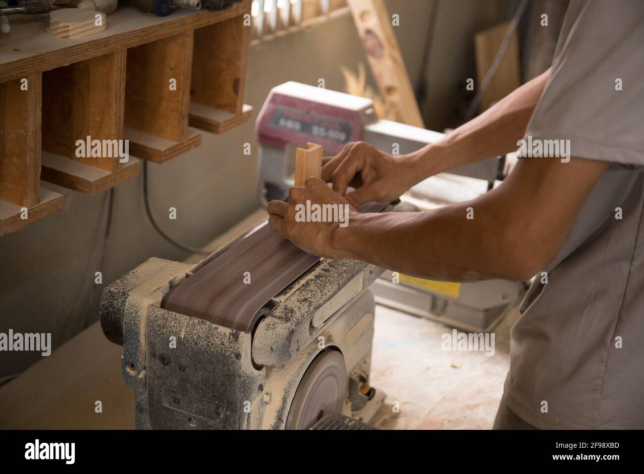 Closeup of a carpenter polishing wood lumber in the workshop with a ...