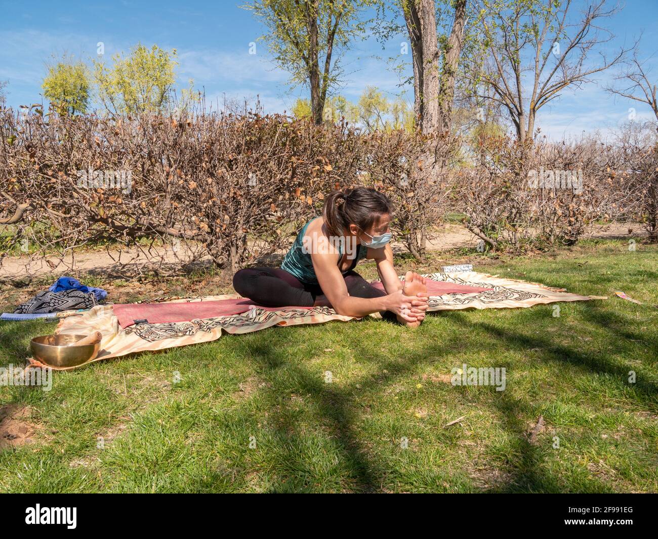 Brunette woman doing yoga class in a park on a sunny day and wearing a ...