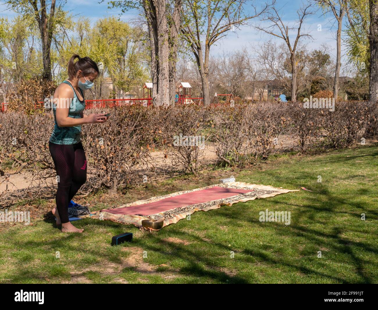 Brunette woman doing yoga class in a park on a sunny day and wearing a ...