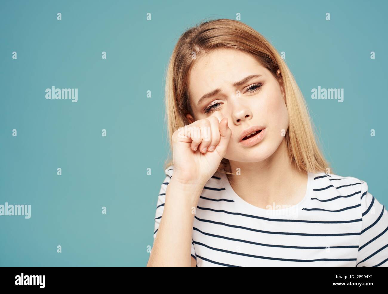 Emotional blonde woman on a blue background gestures with her hands a ...