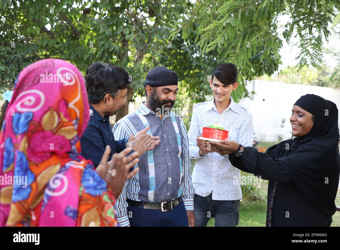Indian people clapping and smiling in the park while a woman gives the ...