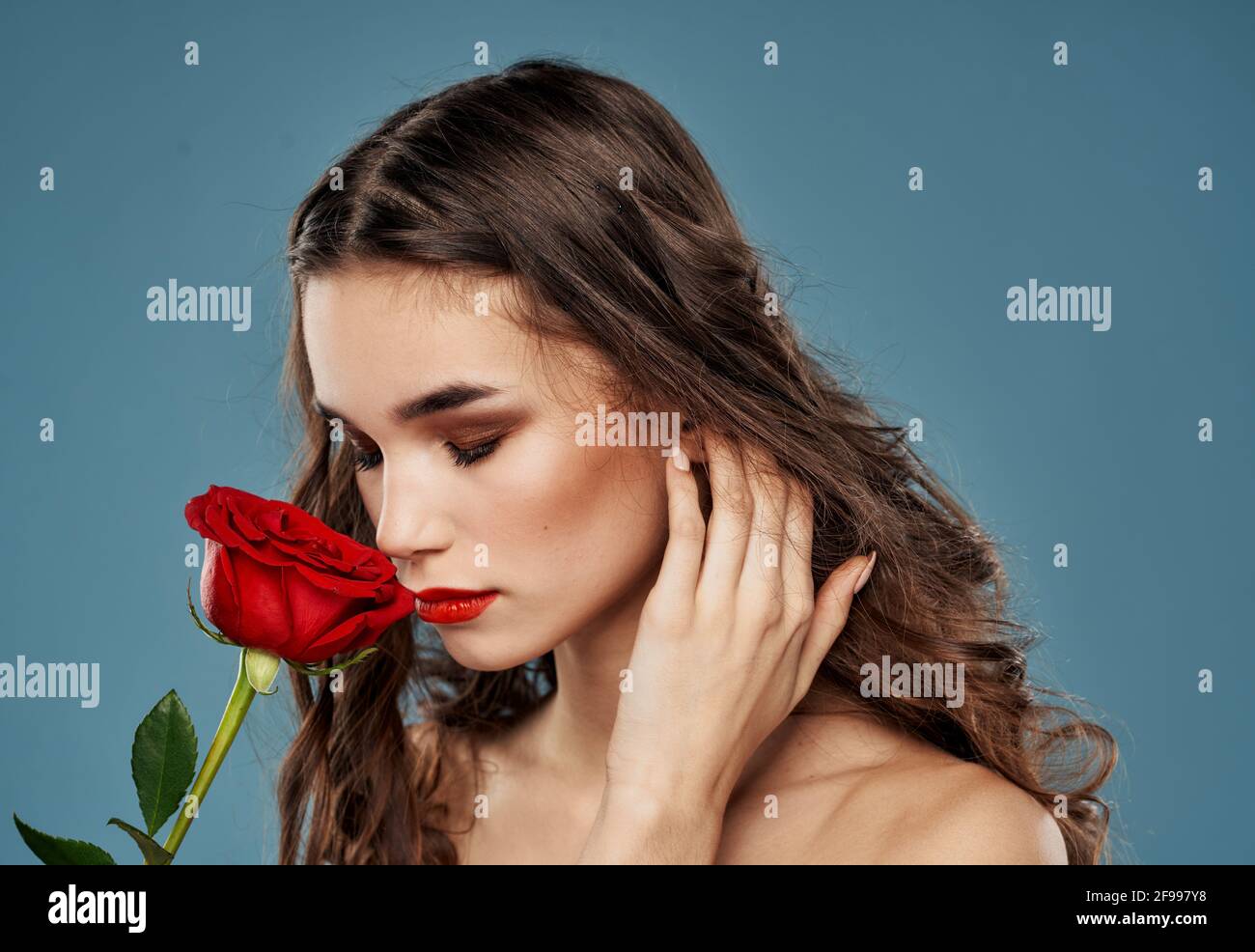 Portrait of a beautiful woman with a red flower on a blue background ...