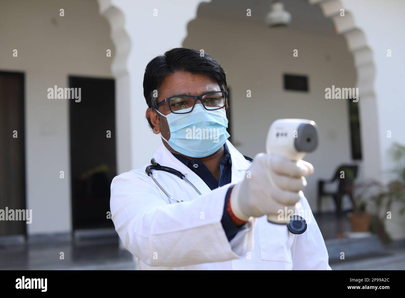 Health worker checking visitor's temperature using infrared digital ...