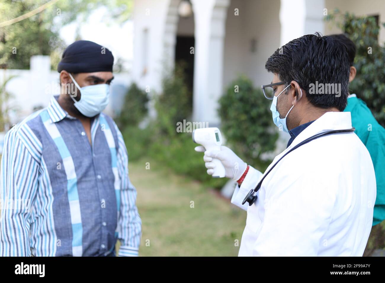 Health worker checking visitor's temperature using infrared digital ...