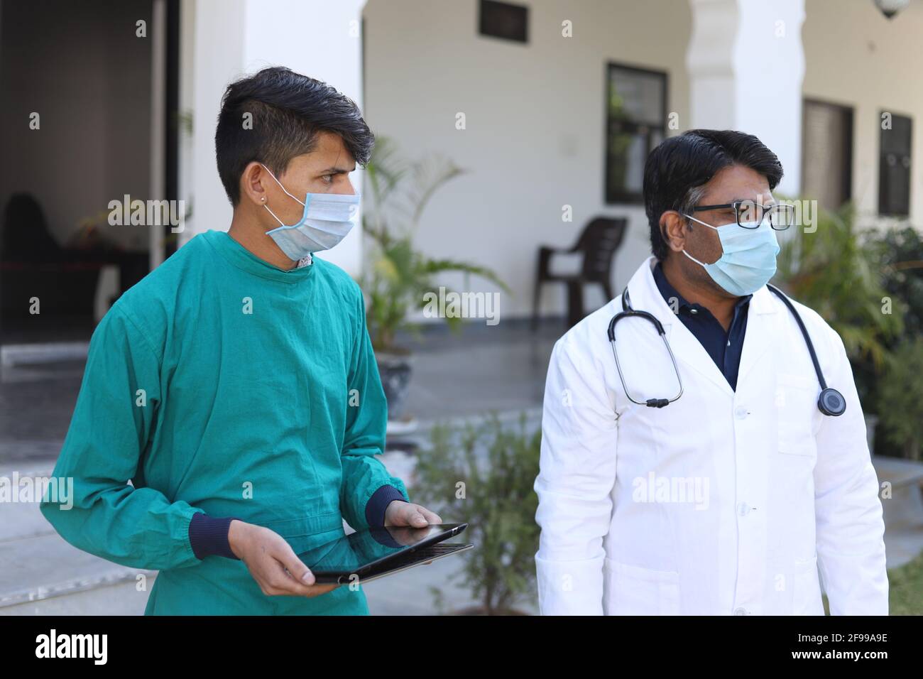 Indian doctor and his assistant with medical uniform and masks standing ...