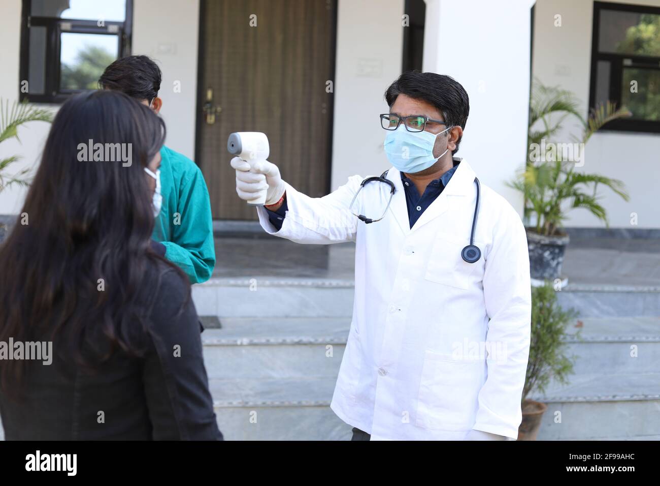 Young doctor measuring the body temperature of his patient with a ...