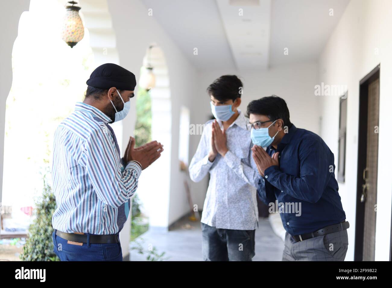 Front view of three Indian men with face masks greeting each other ...