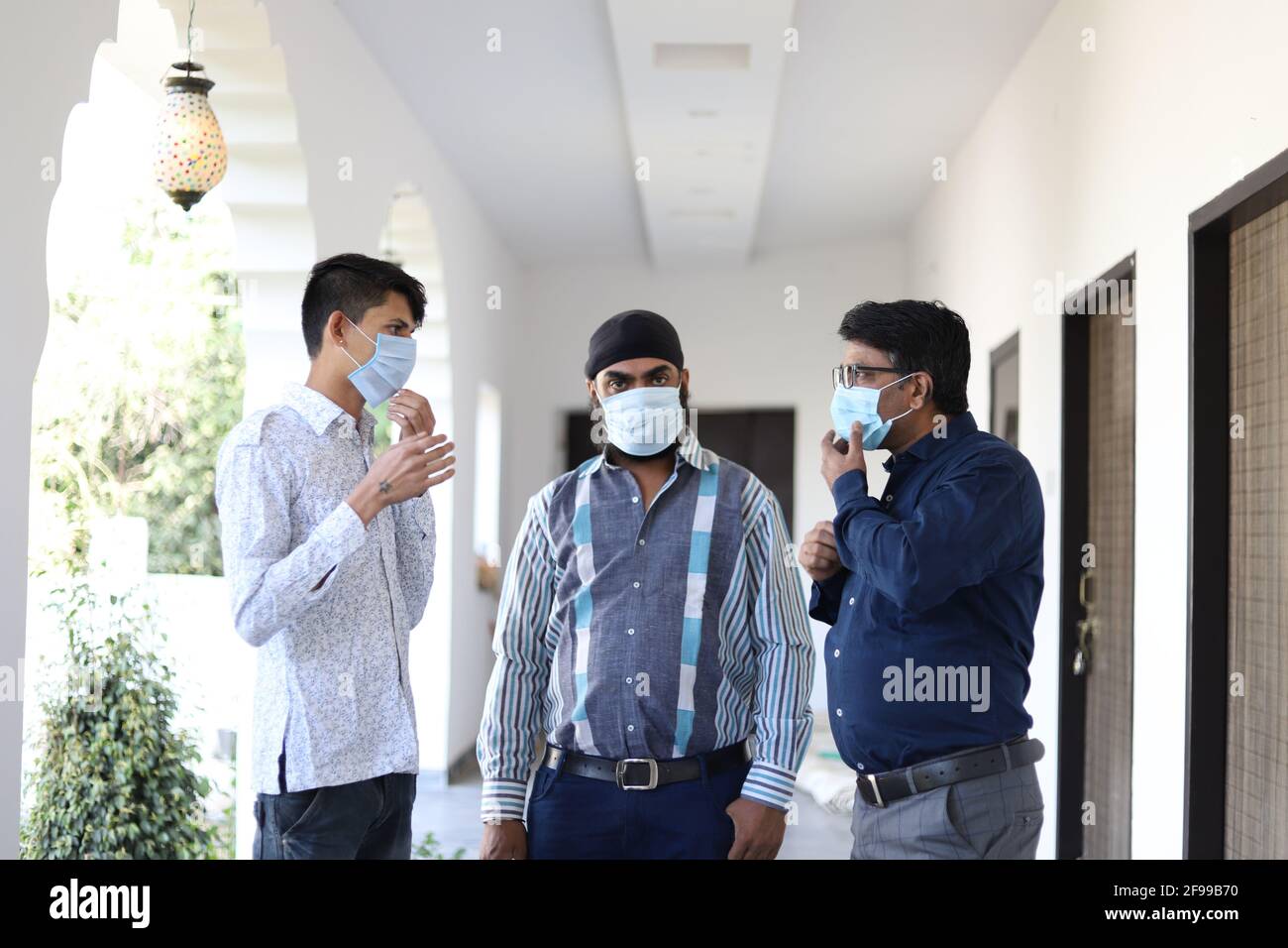 Front view of three Indian men with face masks having a conversation ...