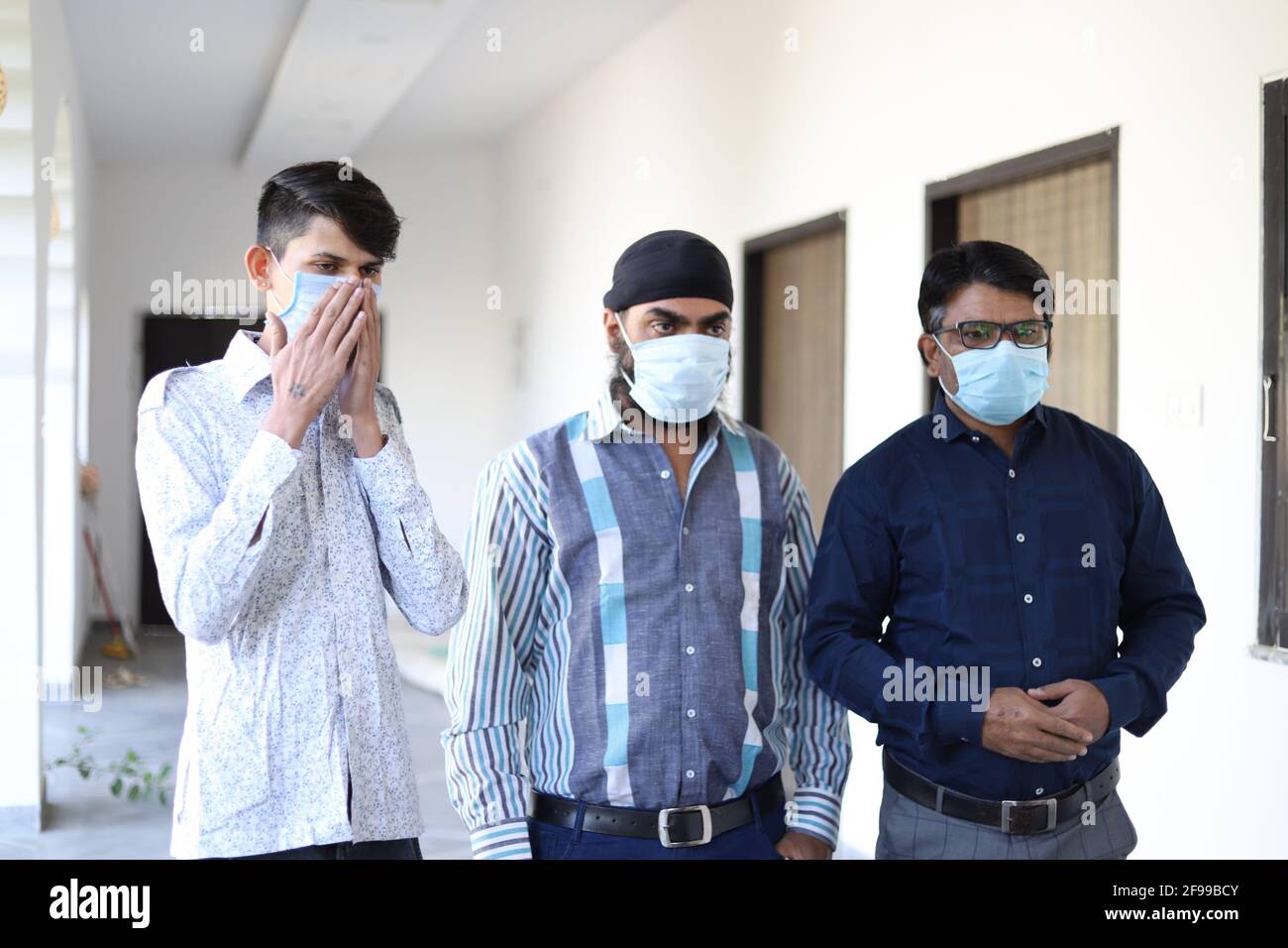 Front view of three Indian men wearing face masks standing outside the ...