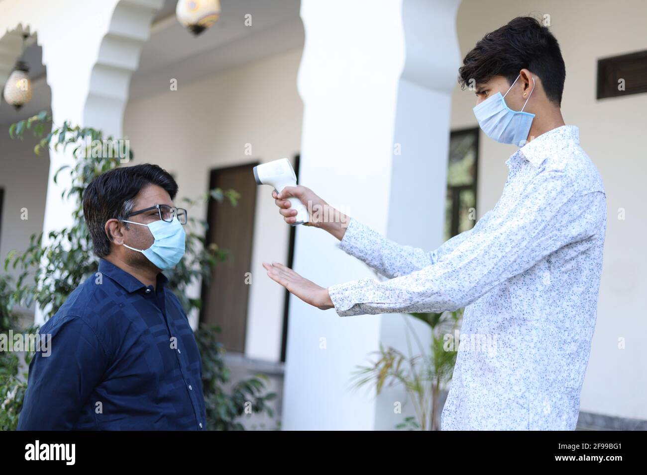 Health worker checking visitor's temperature using infrared digital ...