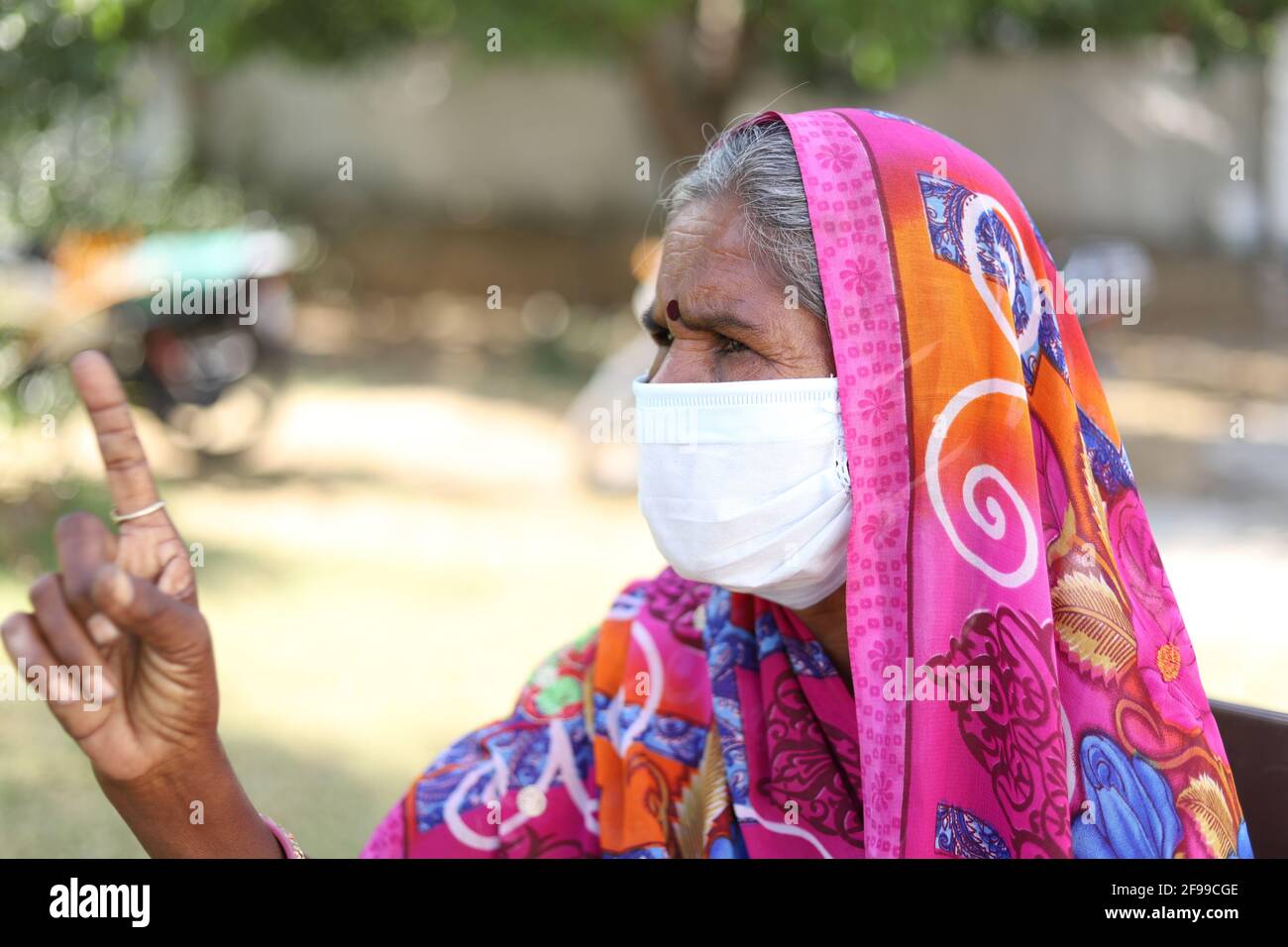 Closeup shot of an Indian woman with a traditional dress and white mask ...