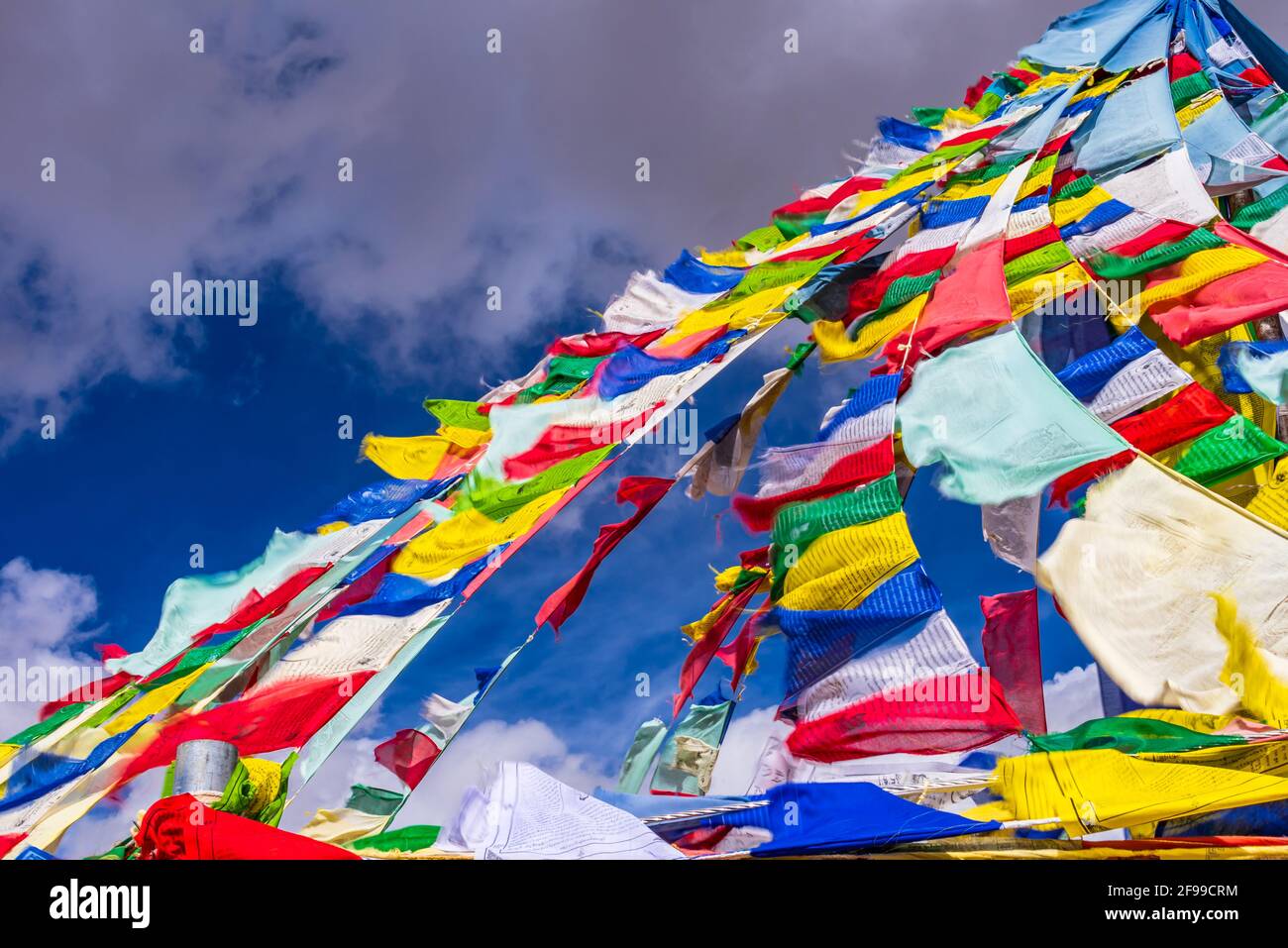 Colorful prayer flags flying in winds with blue sky and Himalayas ...