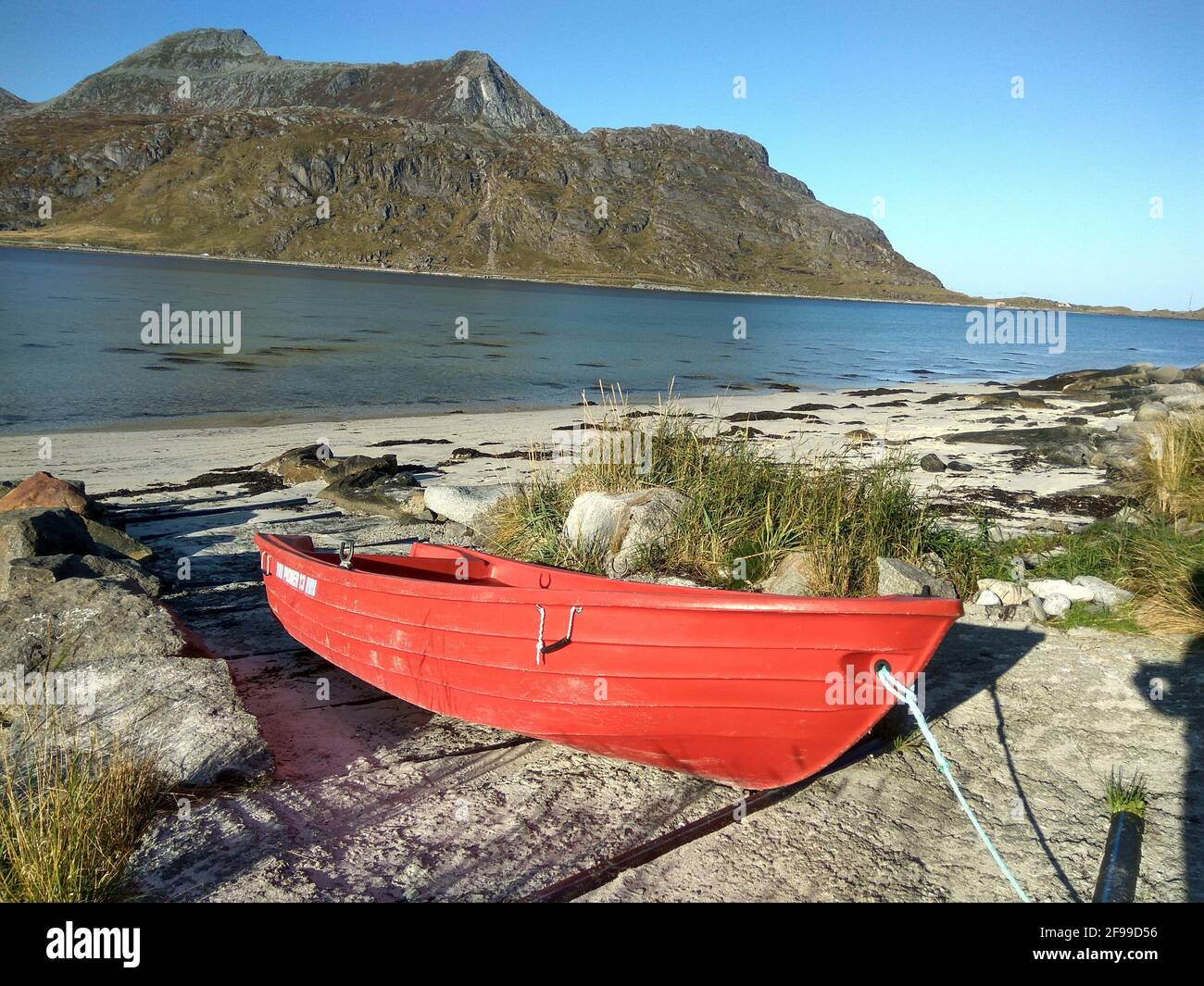 Beautiful view of a calm lake with a rocky mountain and a red boat in ...