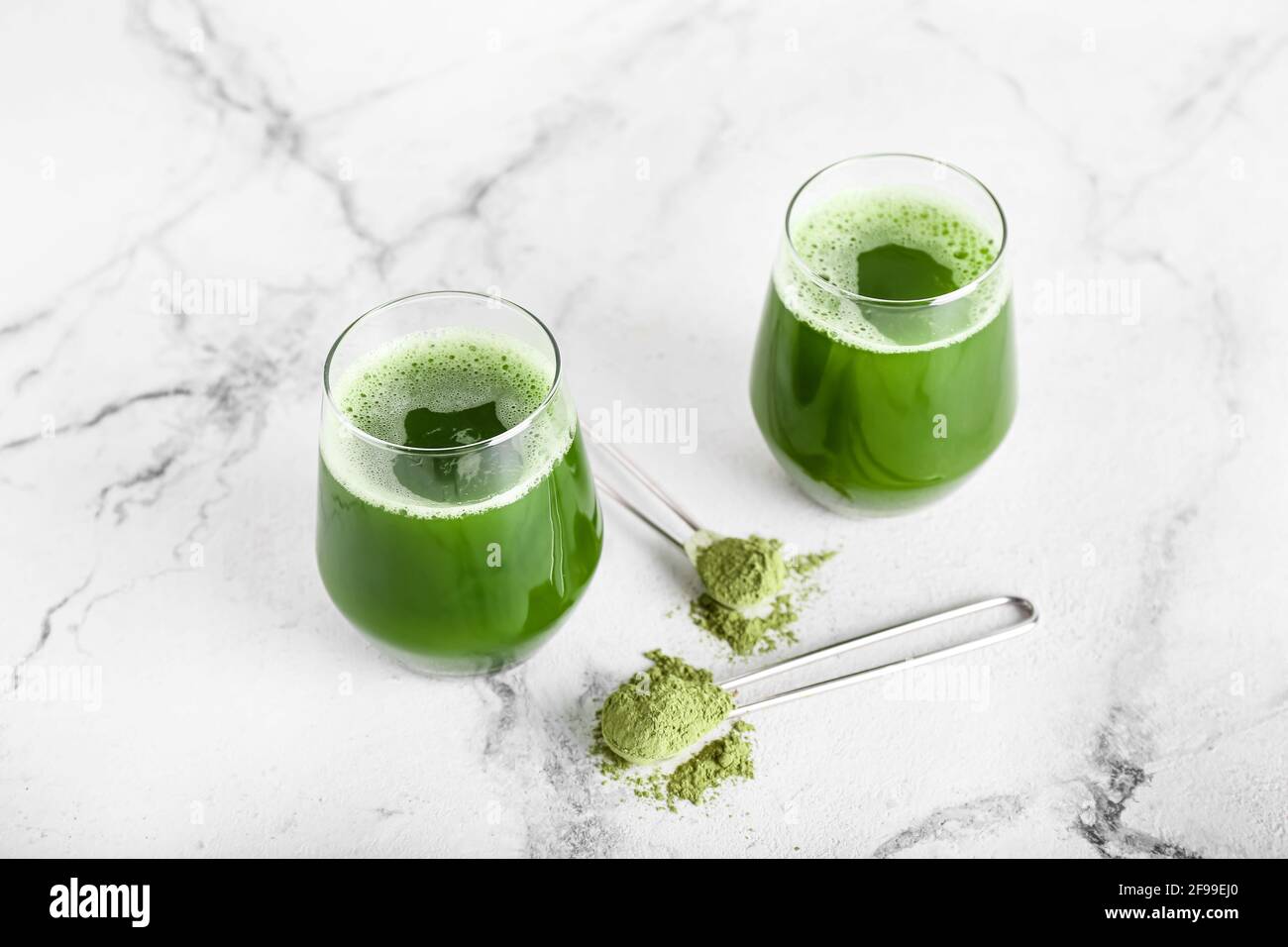 Glasses of matcha tea and powder on light background Stock Photo - Alamy