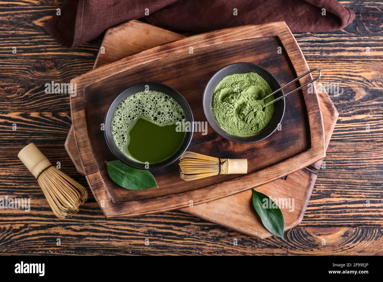Tray with bowl of matcha tea, powder and chasens on wooden background ...