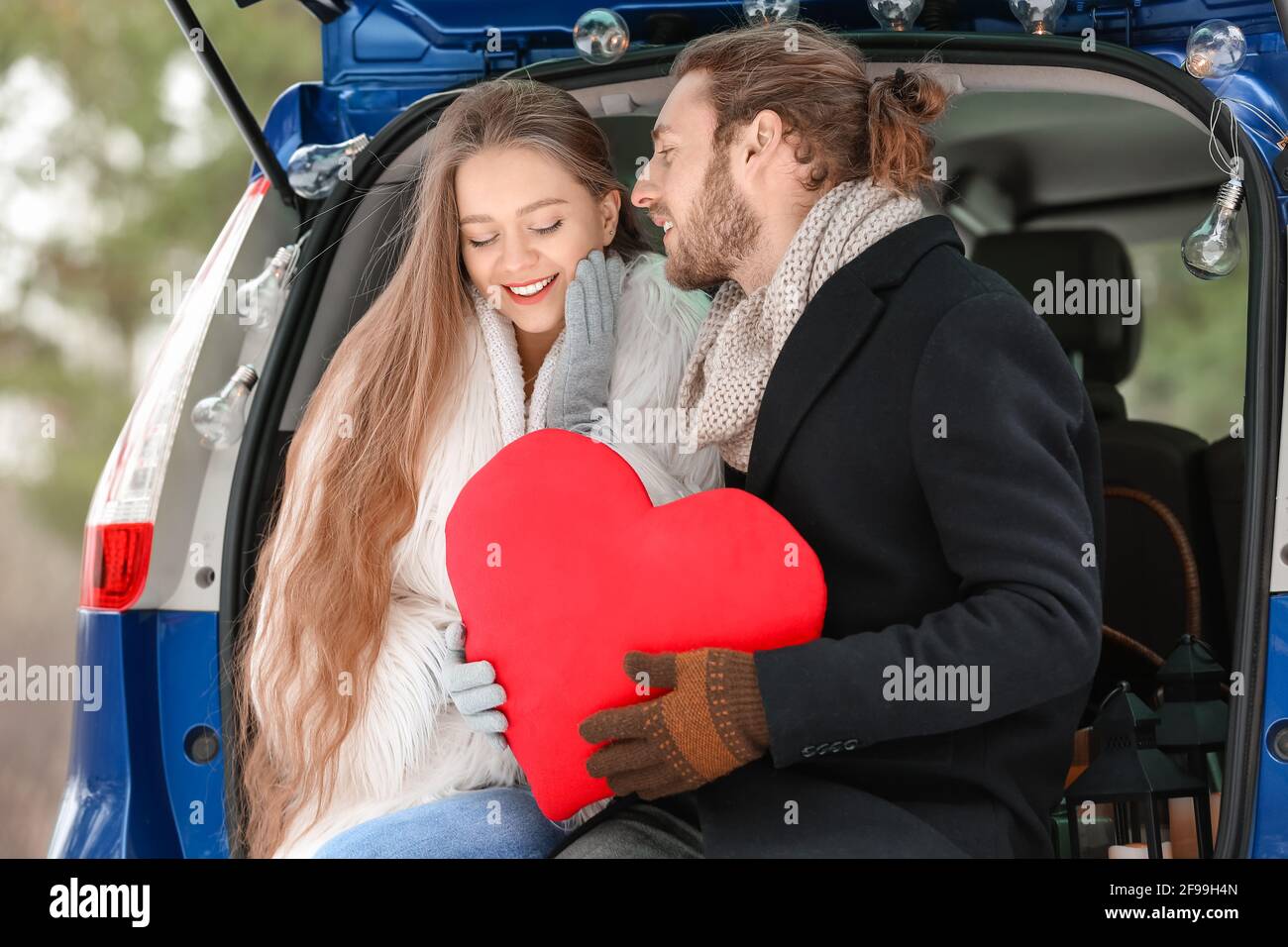 Happy young couple with red heart near car on winter day Stock Photo ...