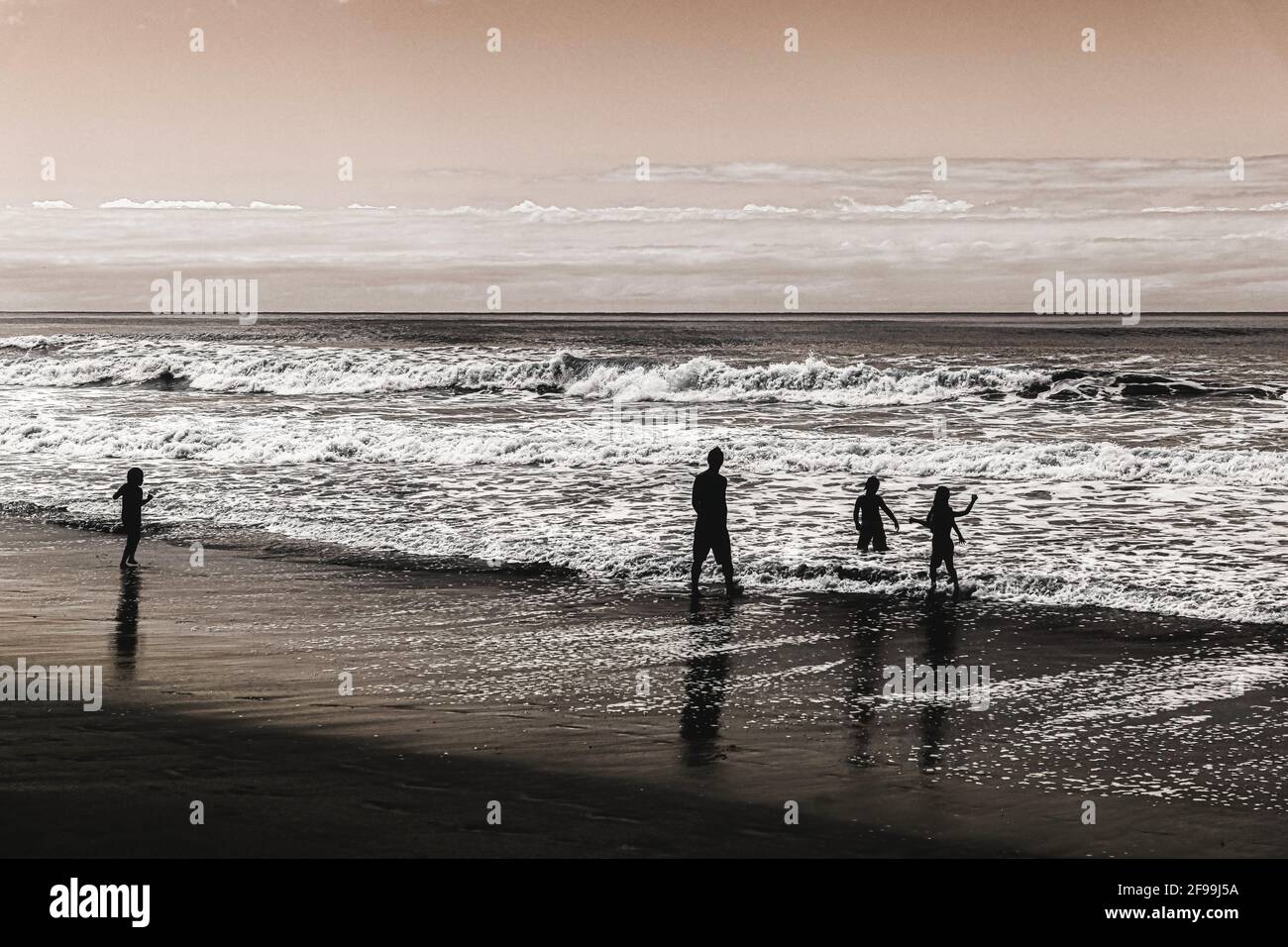 A group of people playing around and having fun on the beach at sunset ...