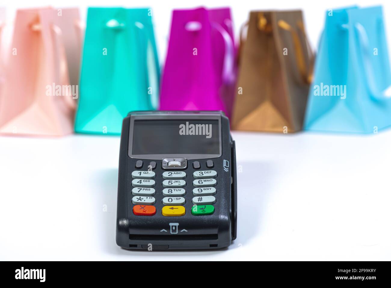 payment terminal and colourful paper bags isolated on light background ...