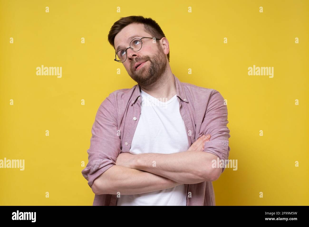 Caucasian man in glasses and casual clothes looks up distantly with ...
