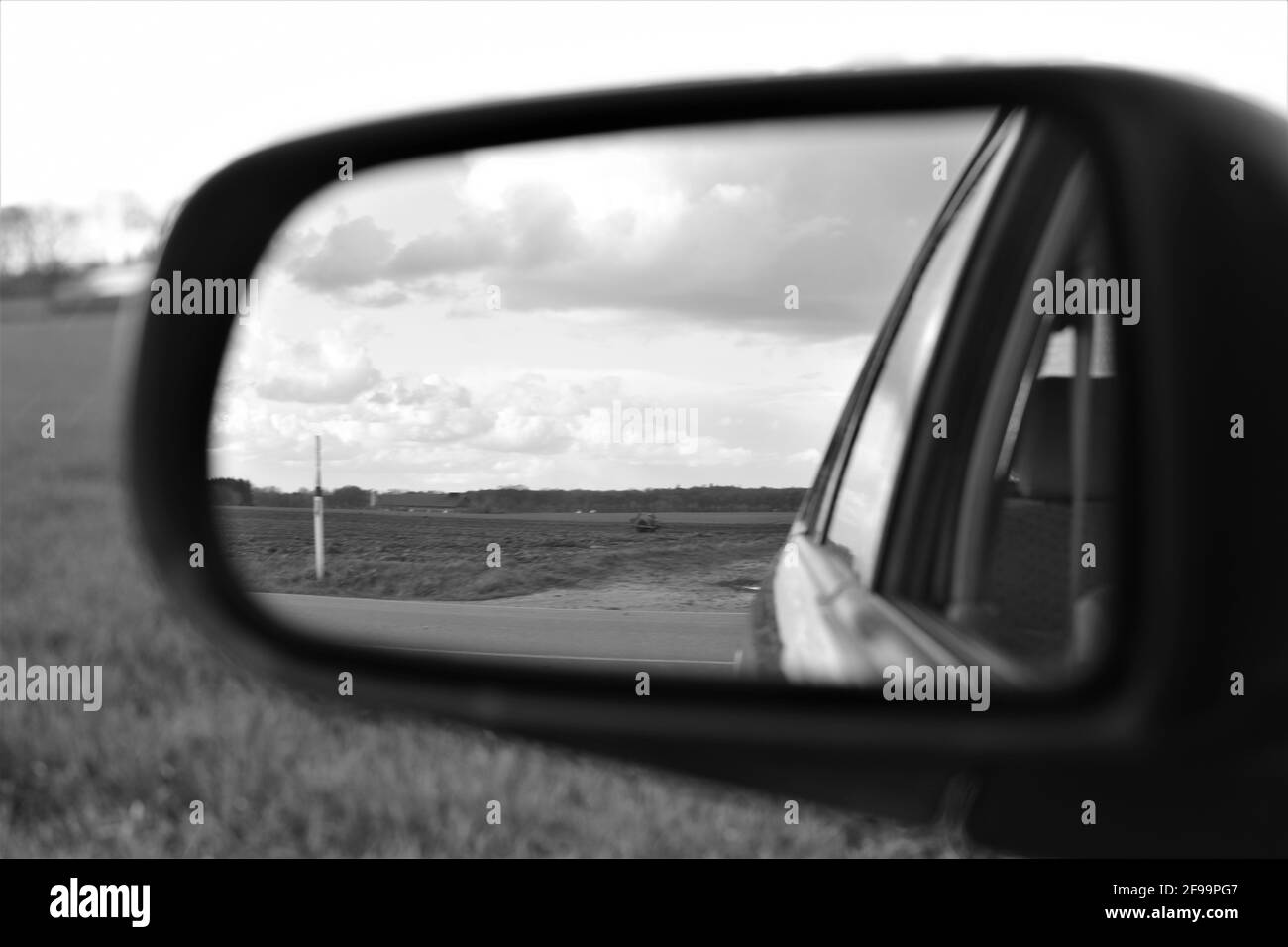 The landscape is reflected in the exterior mirror of a car as a ...