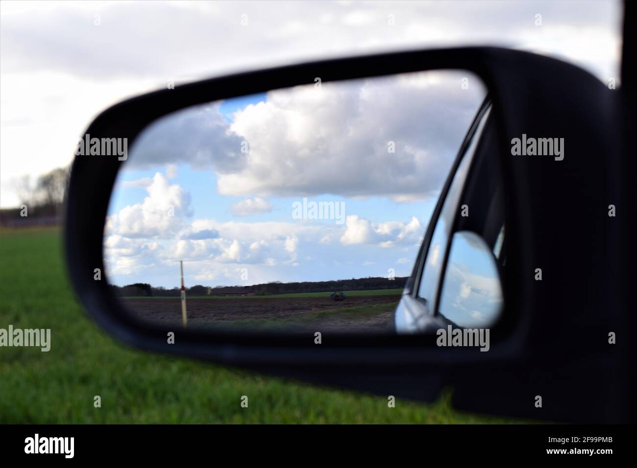 The landscape is reflected in the exterior mirror of a car as a ...