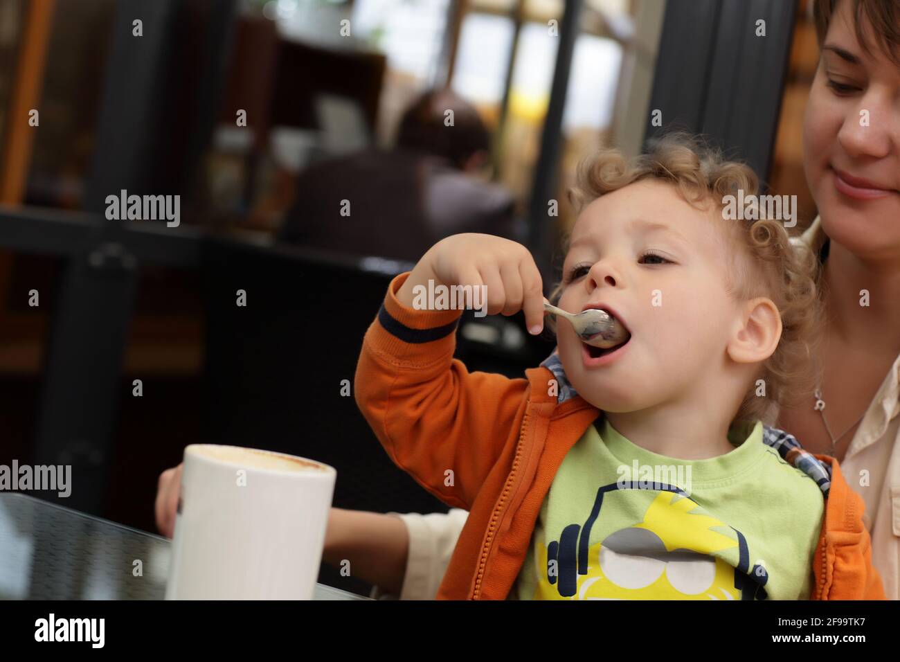 Child is eating froth of coffee in a cafe Stock Photo - Alamy