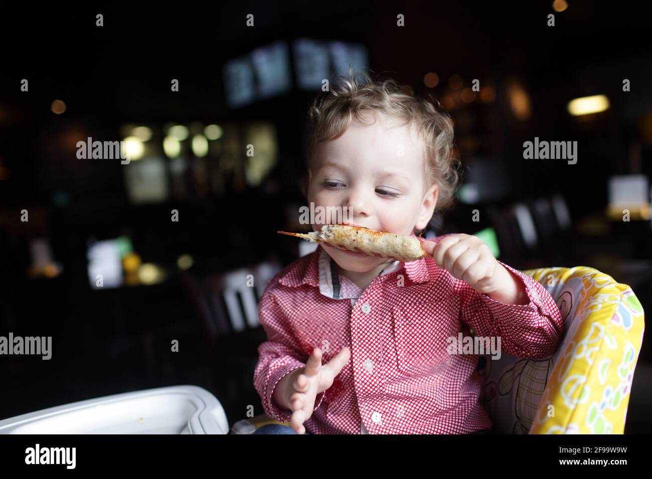 Boy is eating kebab in a high chair at a restaurant Stock Photo - Alamy