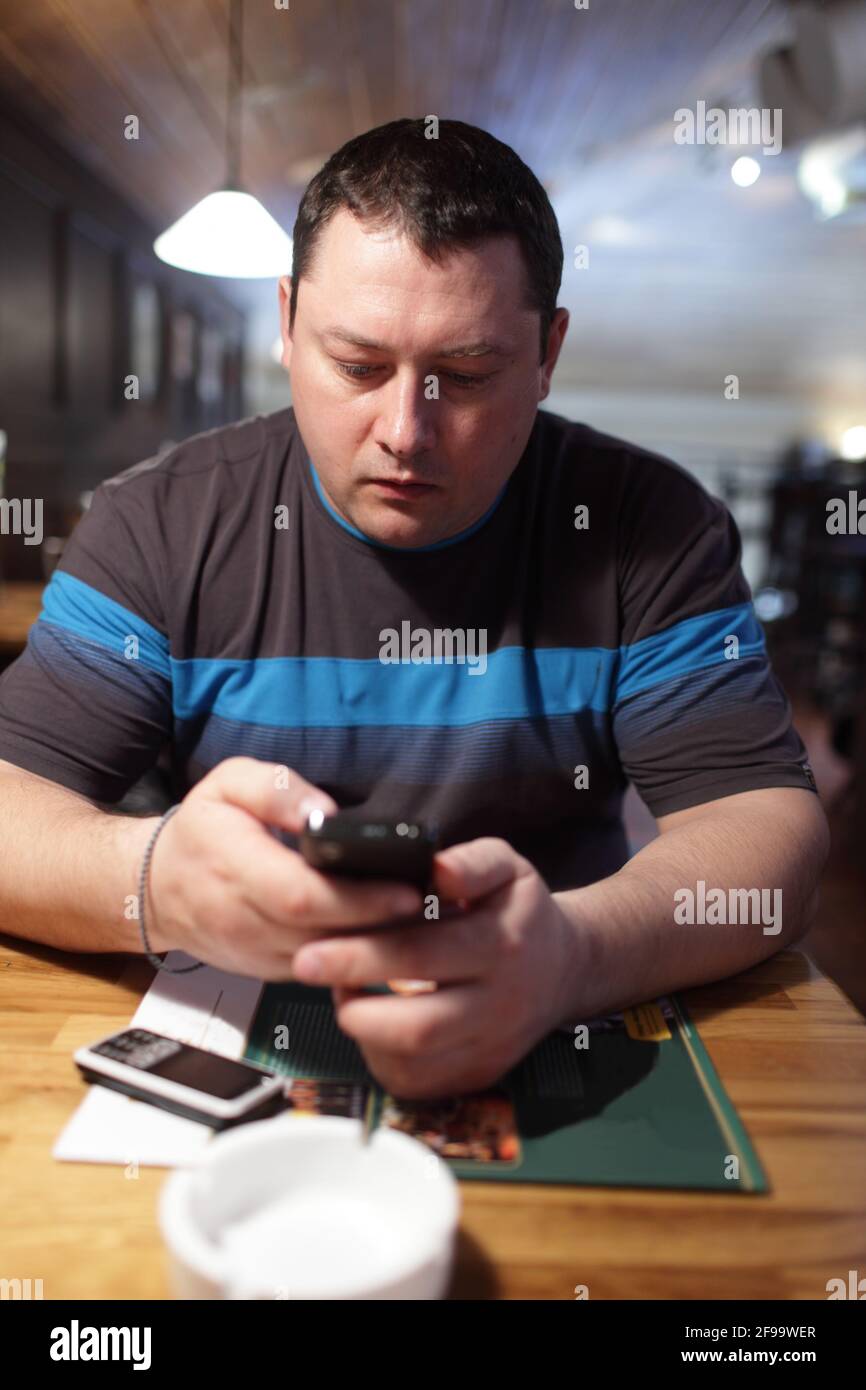 Man is sending email by mobile phone in a pub Stock Photo - Alamy