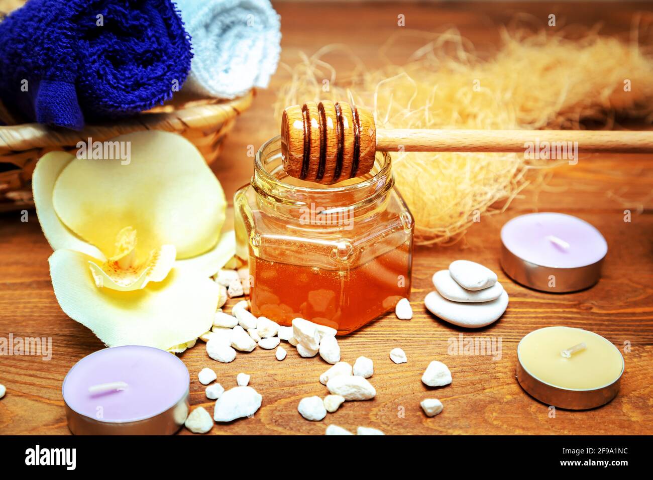 Honey spa treatment. Golden honey jar, orchid flowers, towels and ...