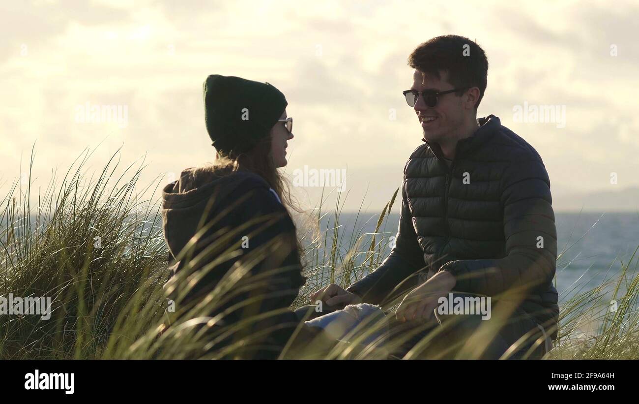 Pretty couple sits at the high reed grass at the beach Stock Photo - Alamy