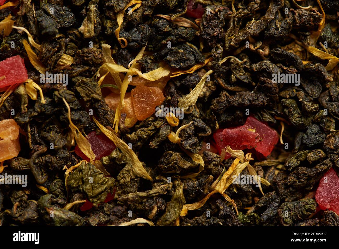 Tea leaves texture with flower petals and fruit pieces as a background ...