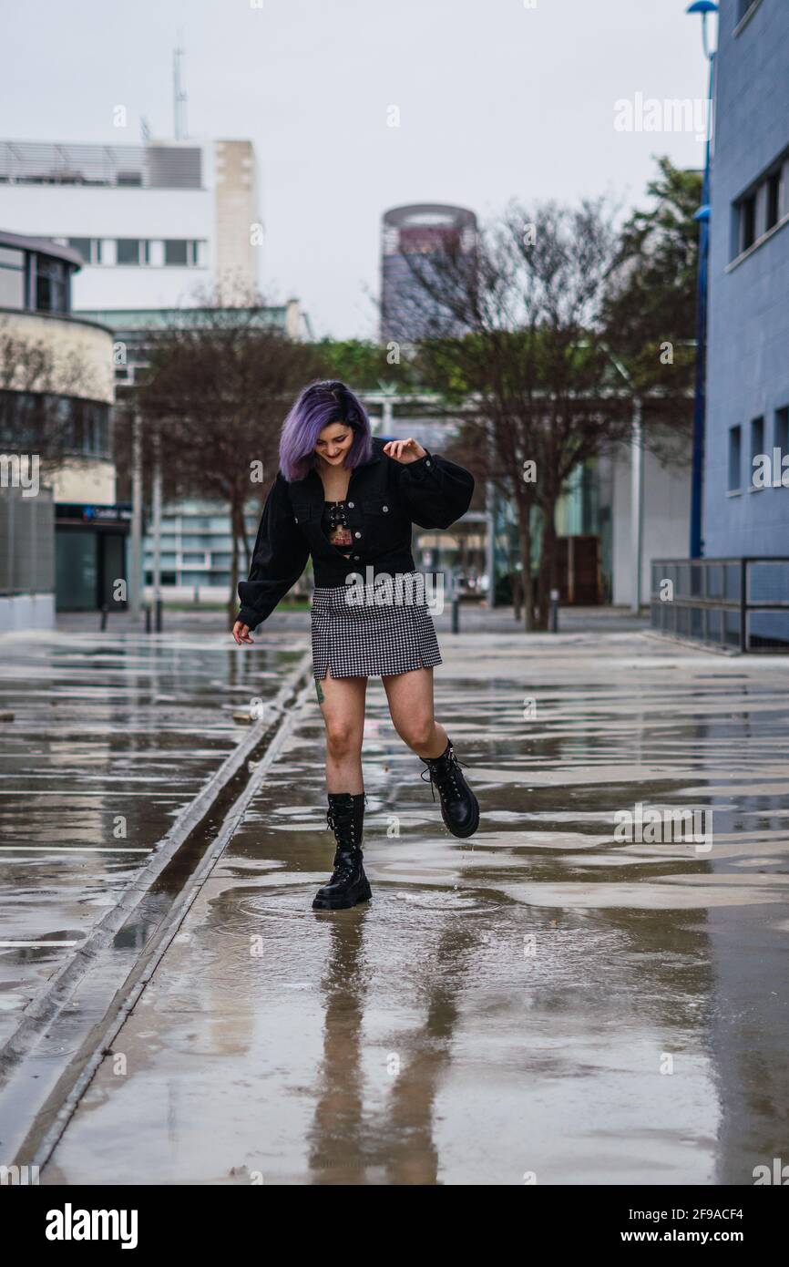 Vertical shot of a stylish European female splashing water from a ...
