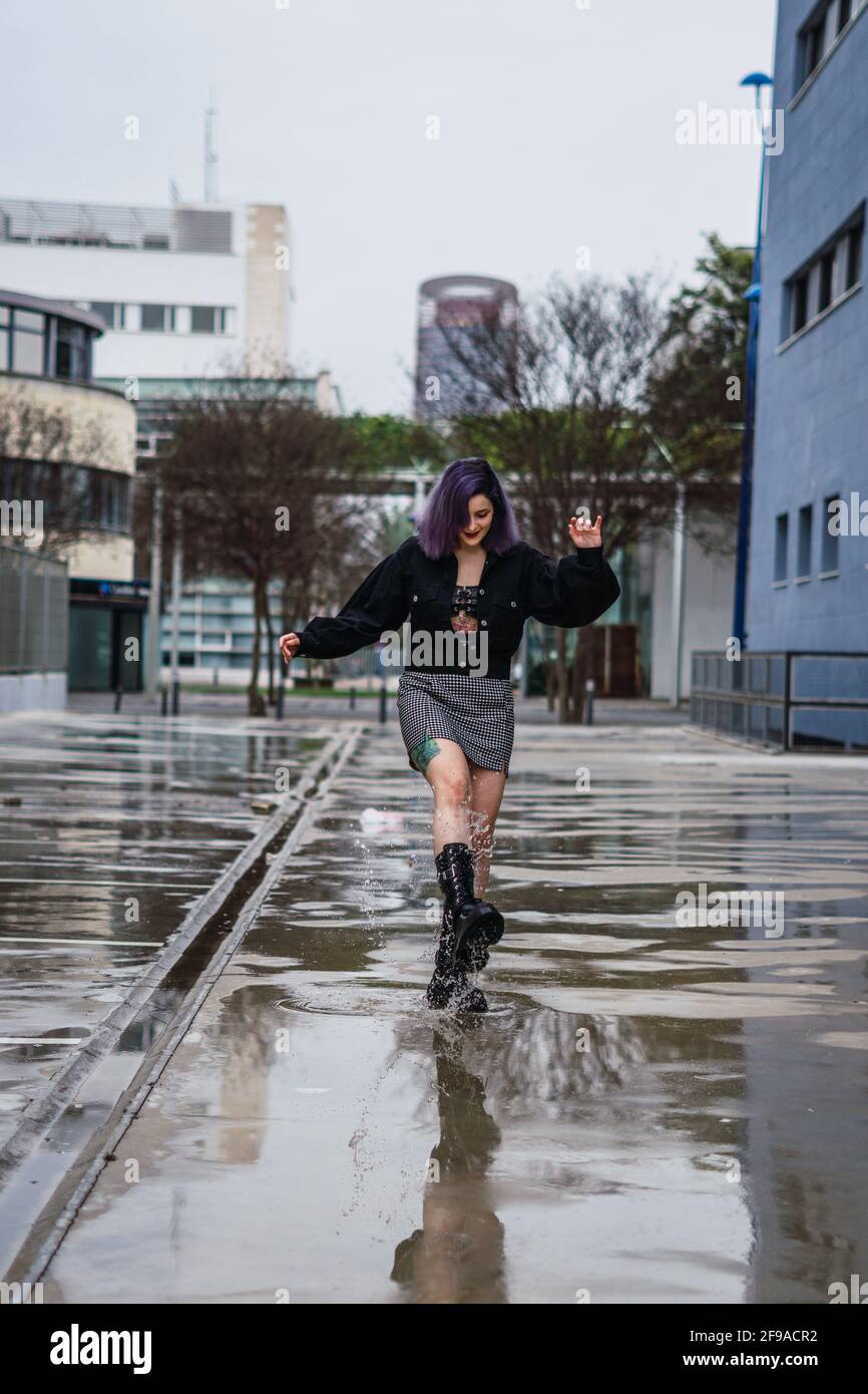 Vertical shot of a stylish European female splashing water from a ...