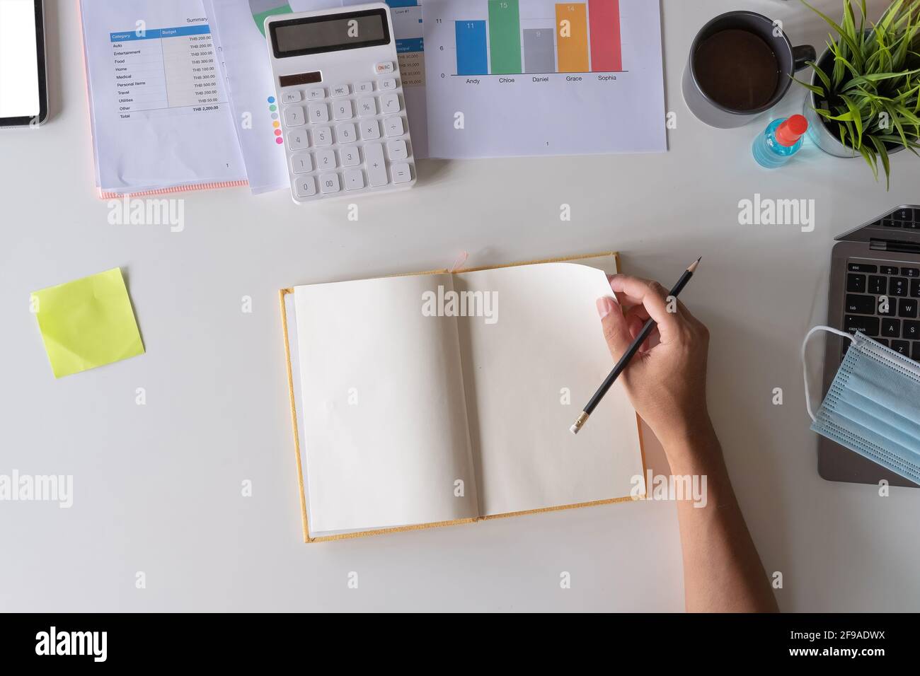 Above view of person taking notes on notepad white working on laptop ...