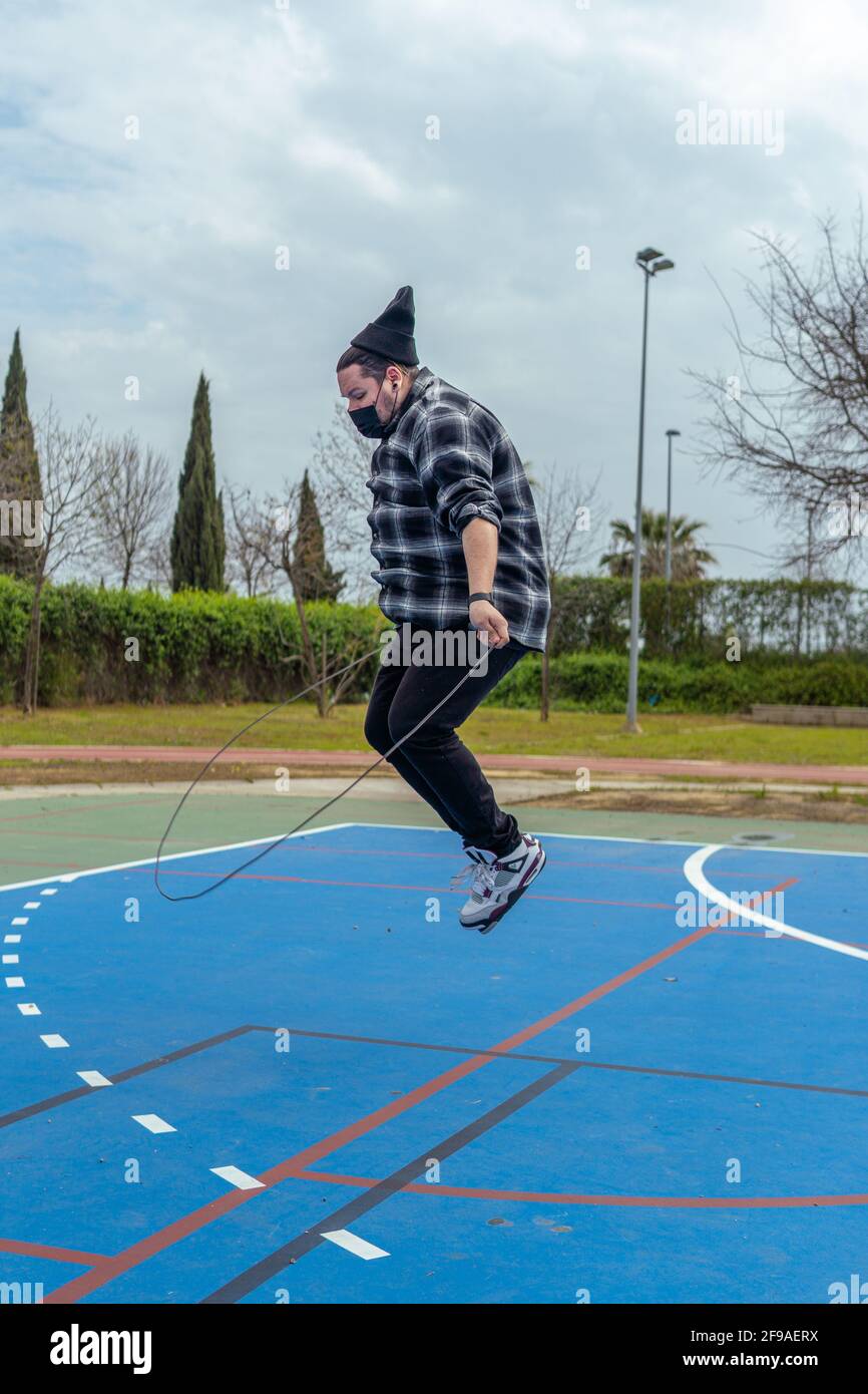 Vertical shot of a young Spanish man in a black mask training with a ...