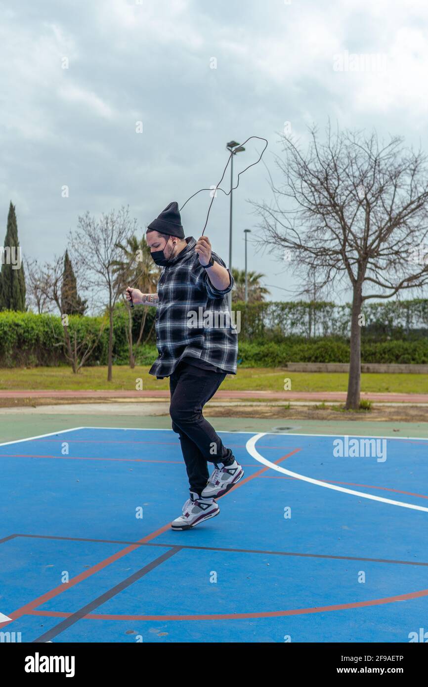Vertical shot of a young Spanish man in a black mask training with a ...