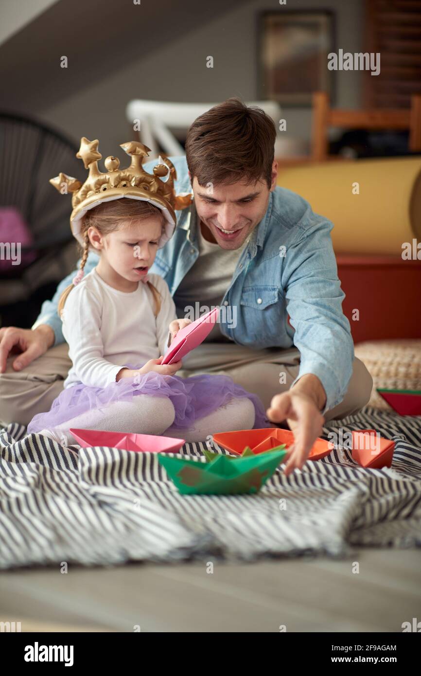 Dad and his little daughter are making boats of paper in a relaxed ...