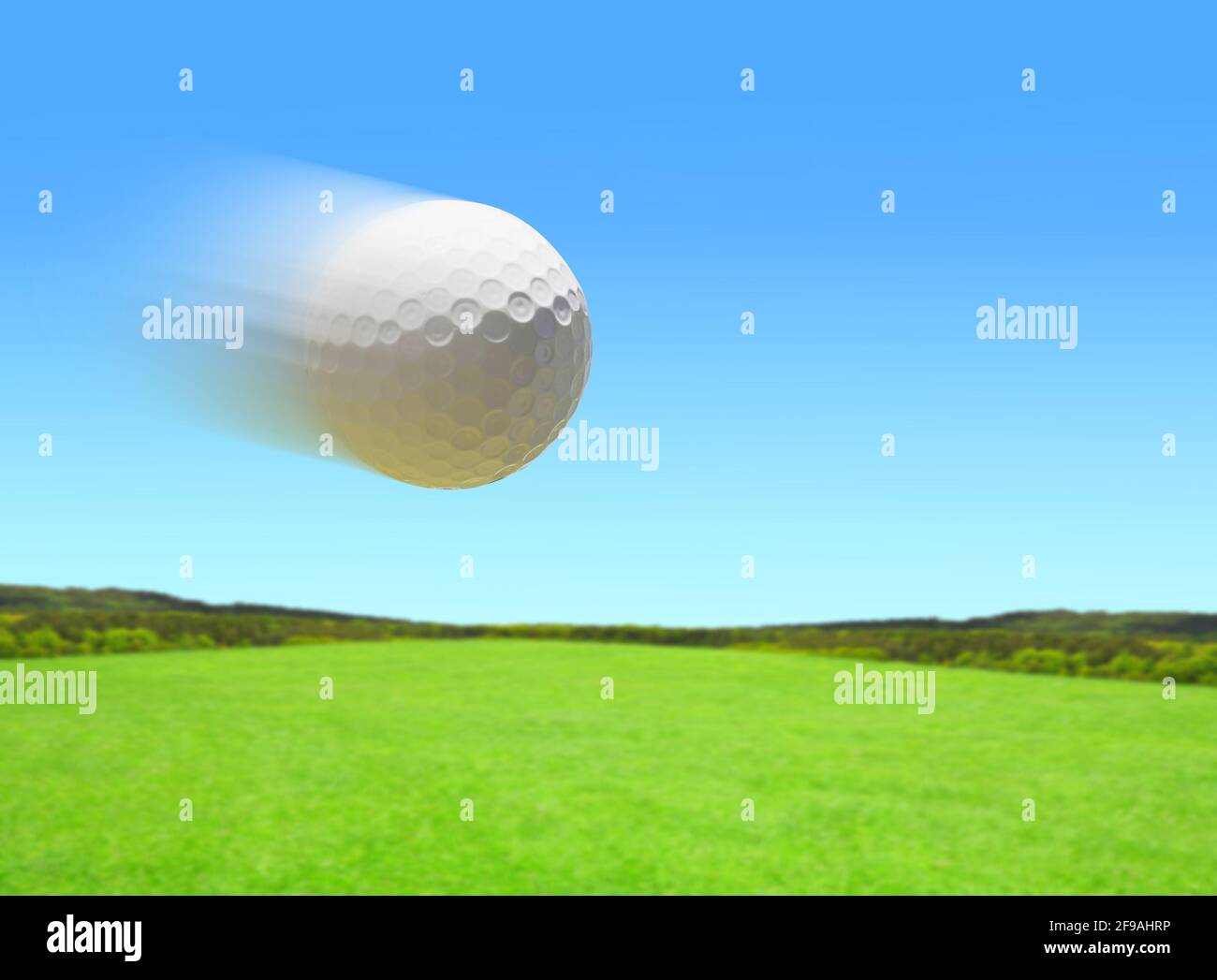 Golf ball flying over green field Stock Photo - Alamy