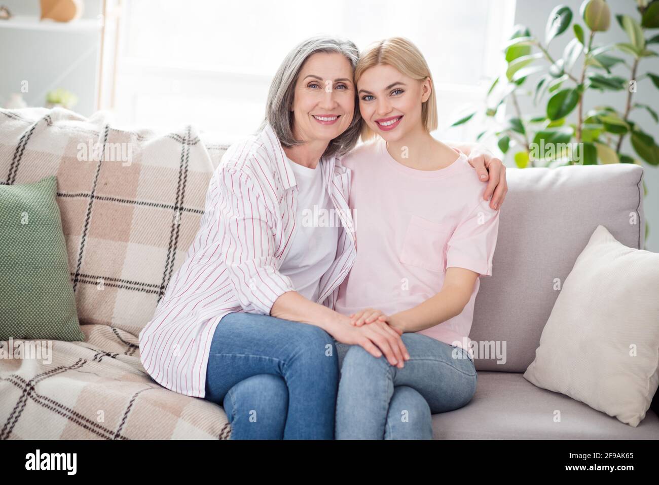 Photo of two pretty positive ladies sit on couch hugging touch hand ...