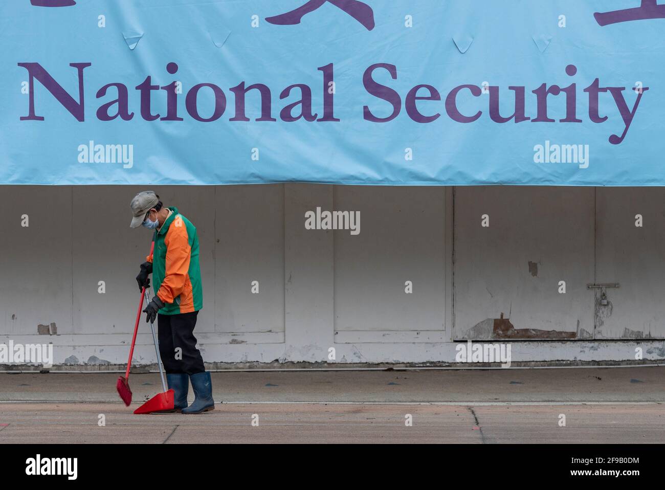 A worker sweeps the ground as a large banner with the phrase "Uphold ...