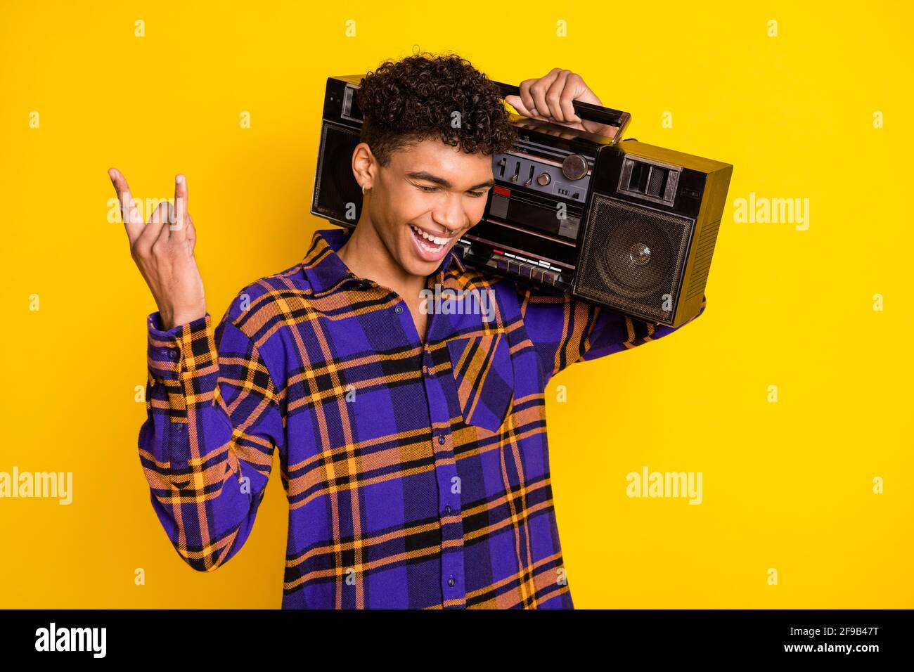 Photo portrait of handsome guy smiling keeping boom box showing heavy ...