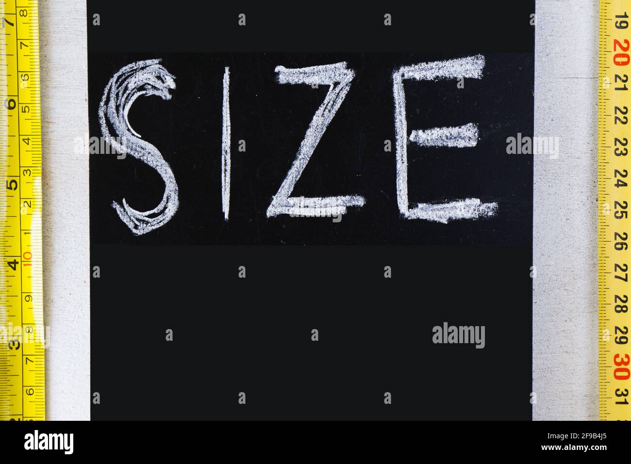 Size text on a blackboard with yellow tape measures on sides Stock ...