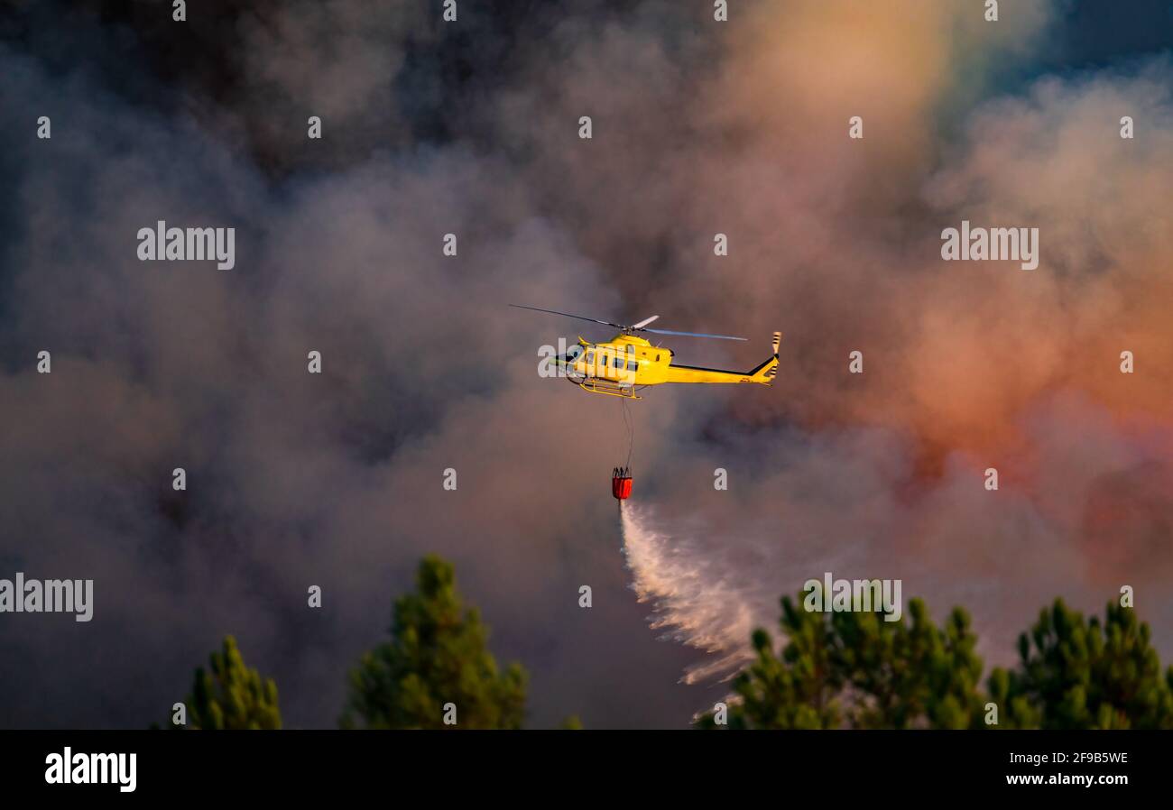 Helicopter throwing a bucket of water to the fire Stock Photo - Alamy